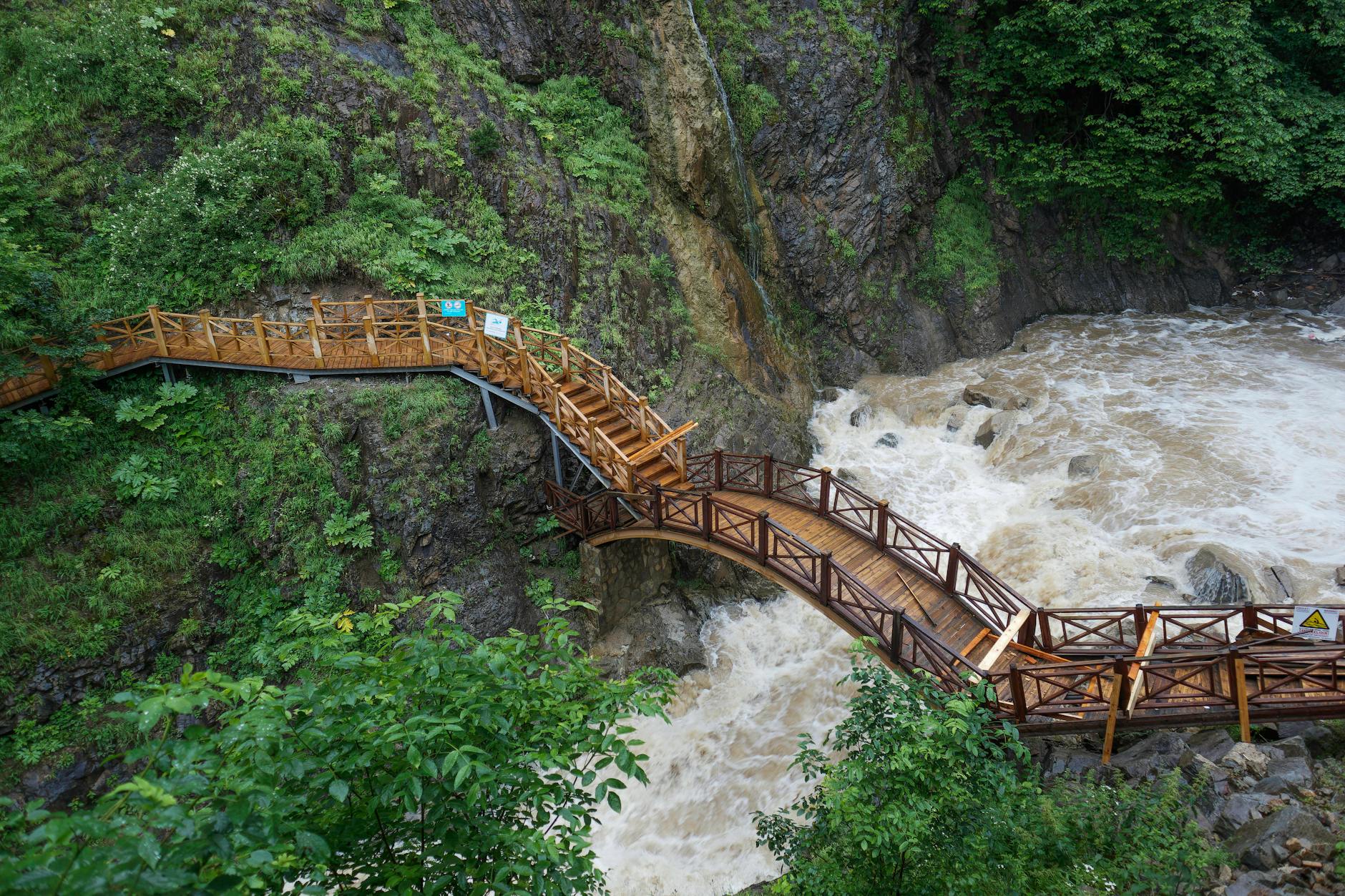 Wooden footbridge through mountain gorge with river