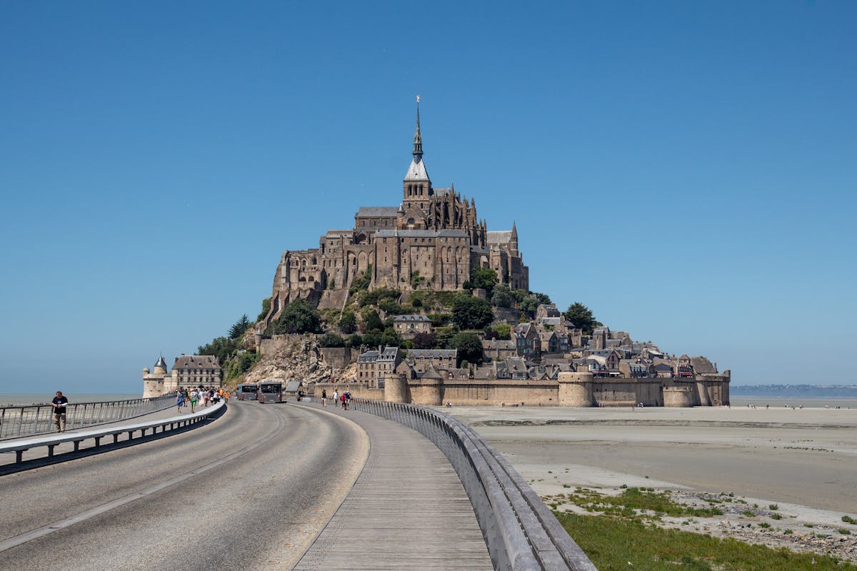 Breathtaking daytime view of Mont-Saint-Michel with tidal flats and blue sky