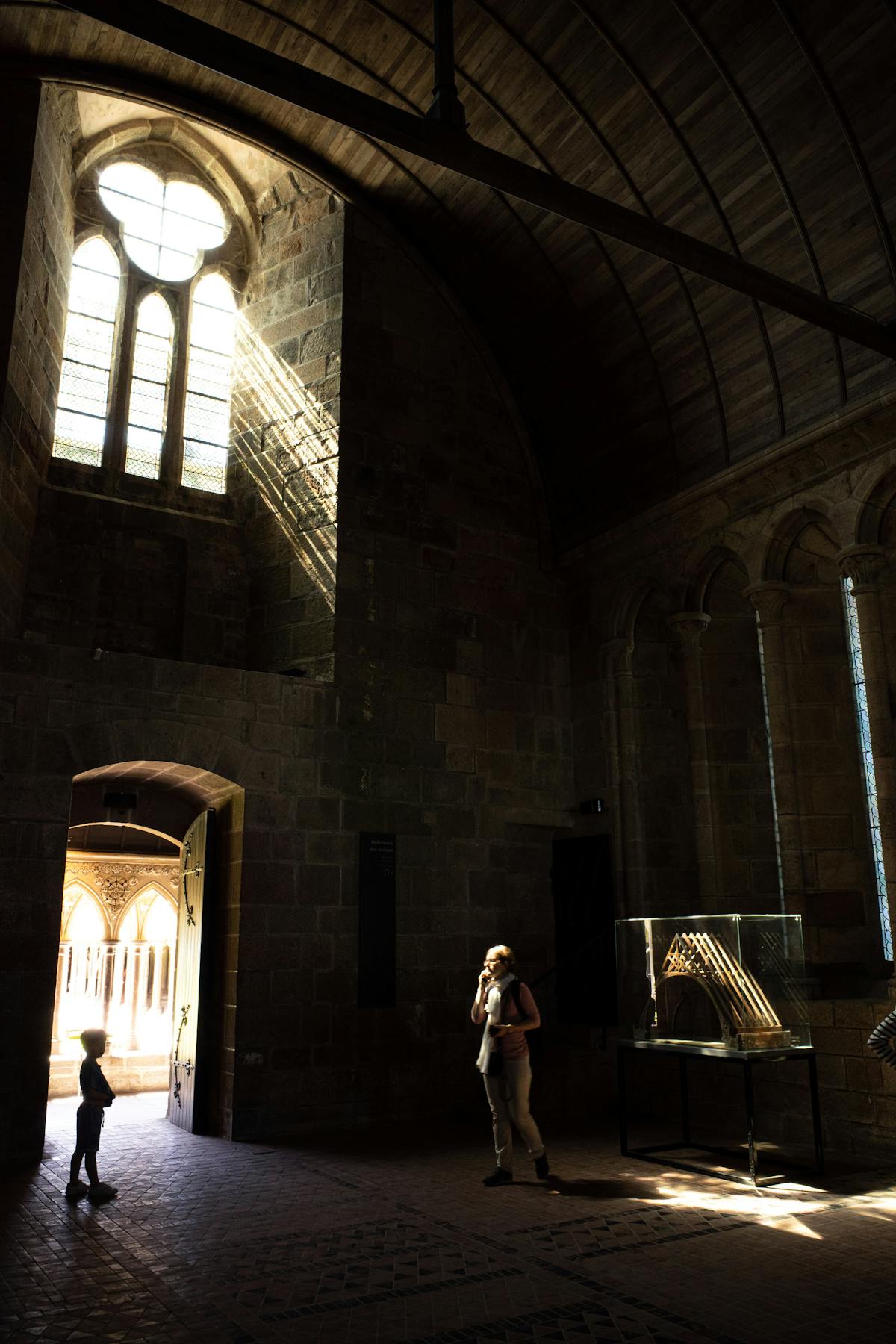 Sunlit interior of Le Mont-Saint-Michel Abbey featuring historic architecture and visitors