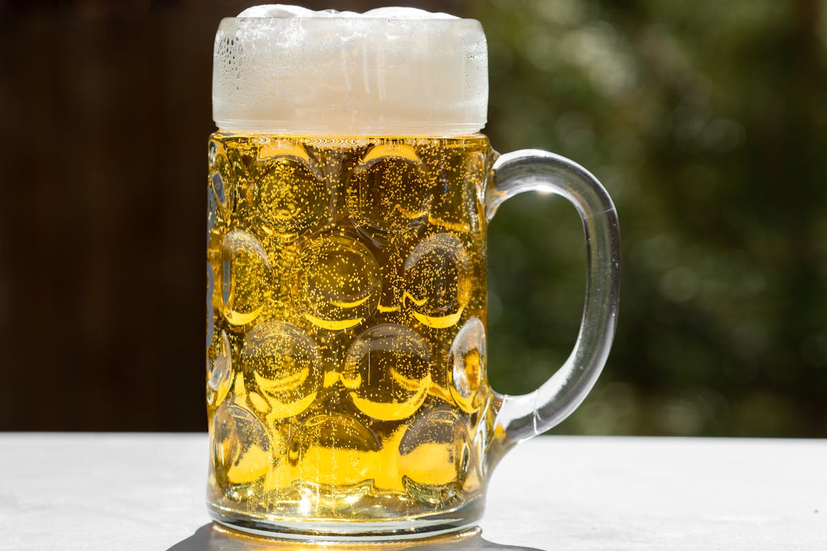 Glass of golden lager beer with frothy head served outdoors in Munich