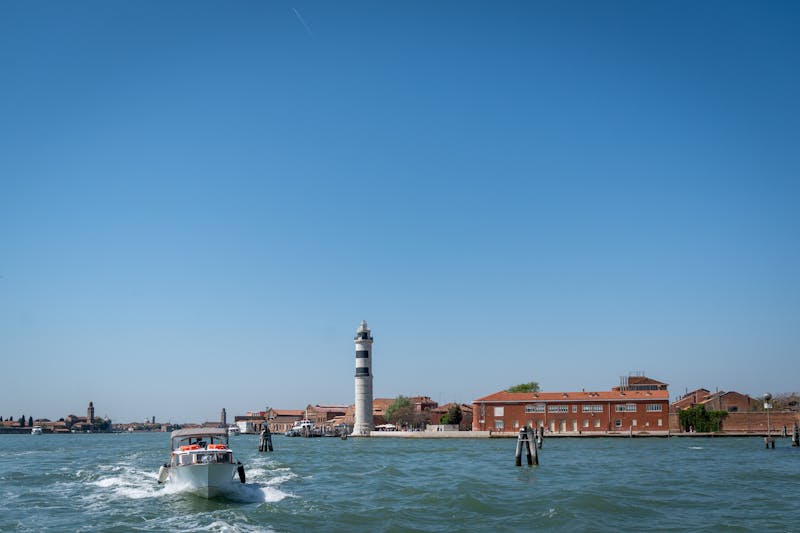 A speedboat passing near the iconic lighthouse on Murano island in the Venice lagoon