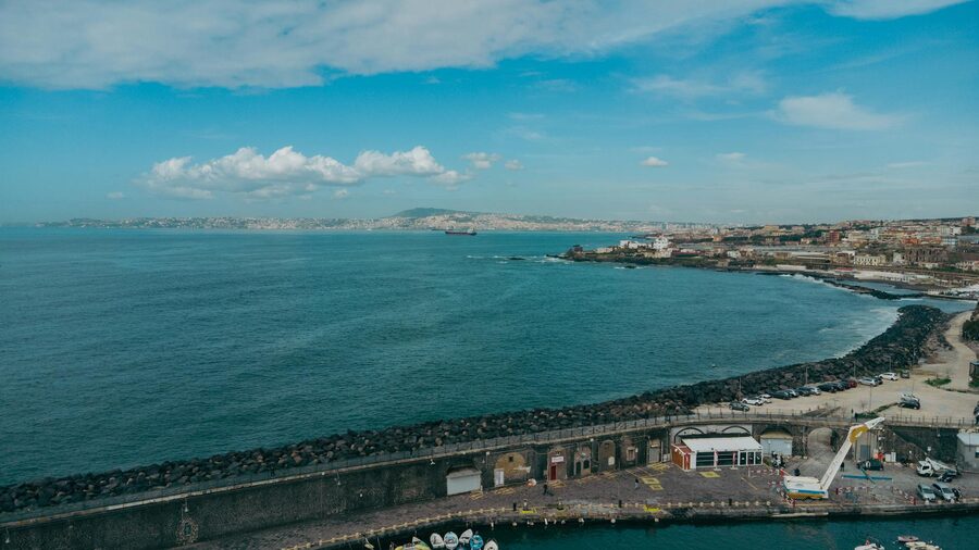 Aerial view of the Naples coastline featuring the bay cityscape and distant mountains