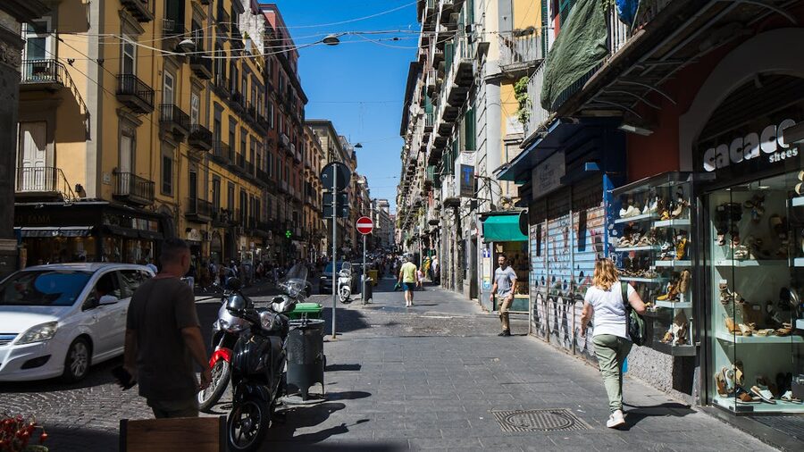 Sunny street view in Naples with shops and pedestrians walking