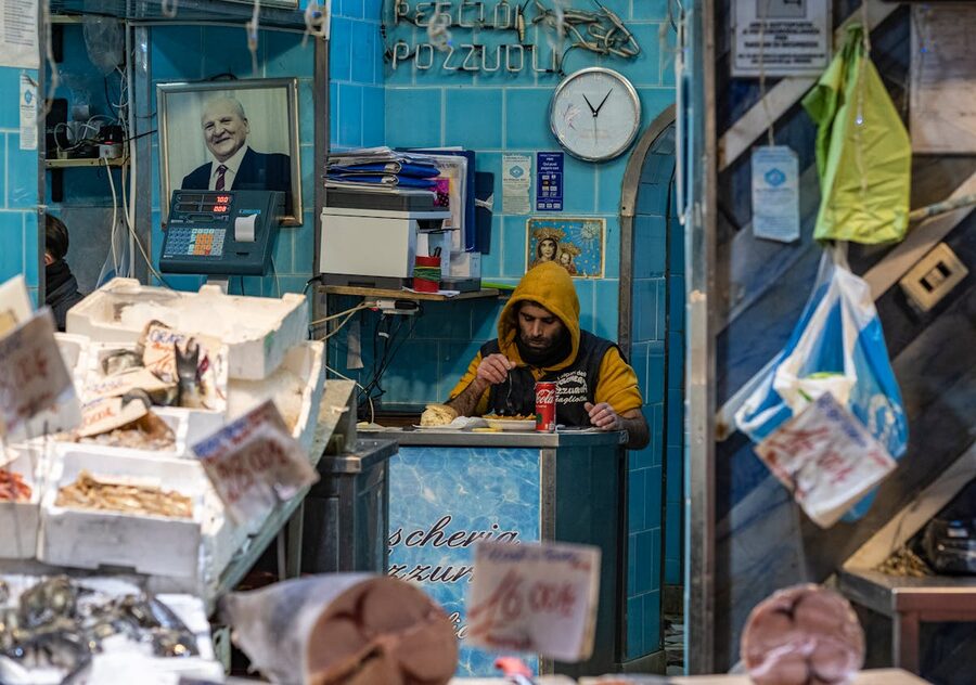 Street market vendor eating and working in Campania Italy surrounded by goods