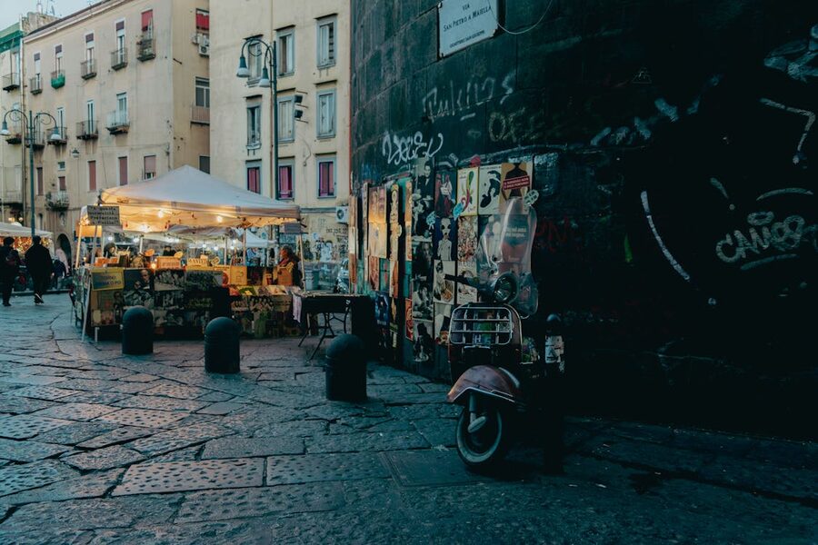 People walking through an evening street market in the historic center of Naples Italy