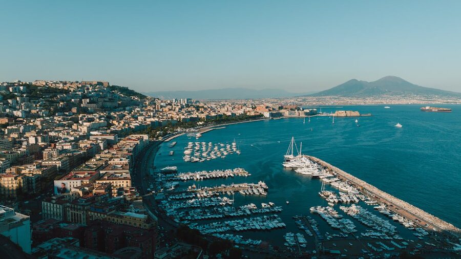 Aerial view of Naples harbor with boats and city skyline under blue sky