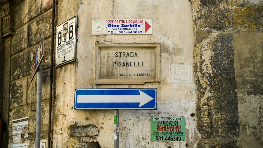 Textured old street signs mounted on a rustic building wall in Naples