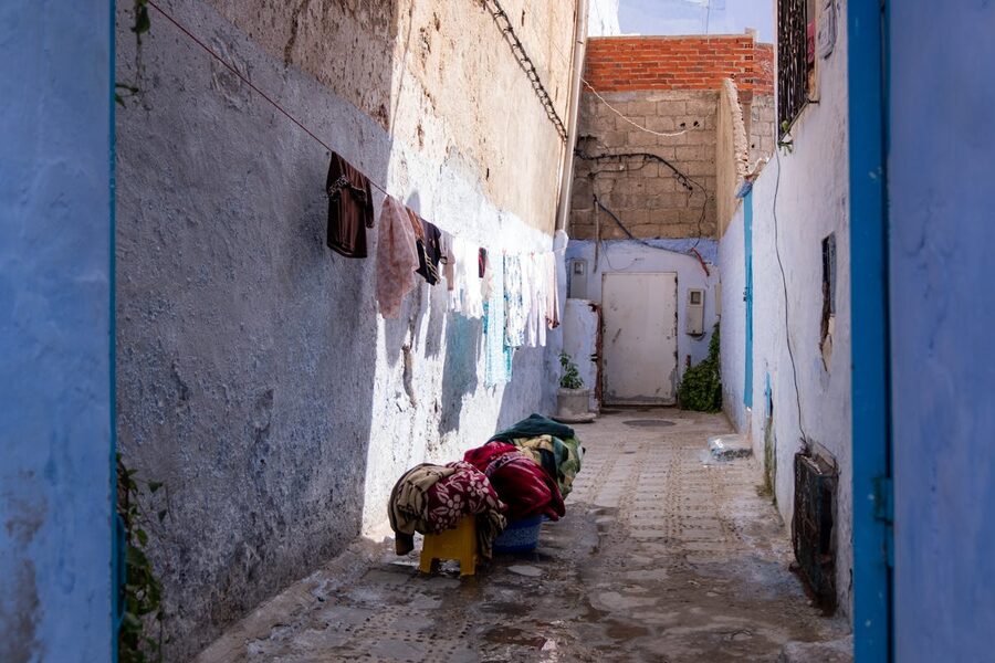 Sunlit narrow alley with clothes hanging on lines between buildings