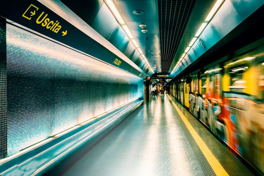 Interior of a Naples metro station with an arriving train and illuminated platform