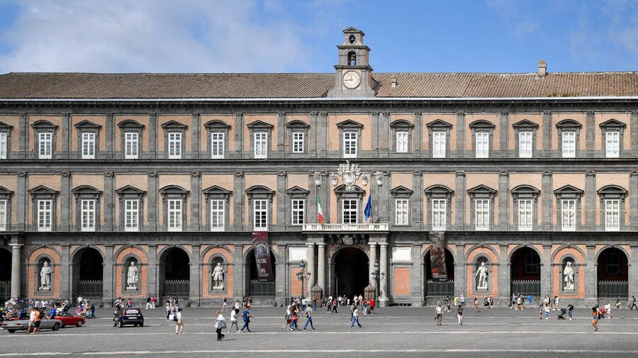 People strolling in Piazza del Plebiscito with the Royal Palace in Naples Italy