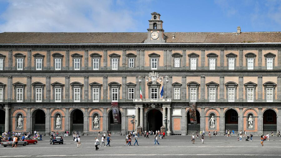 People walking in Piazza del Plebiscito with the Royal Palace facade in Naples