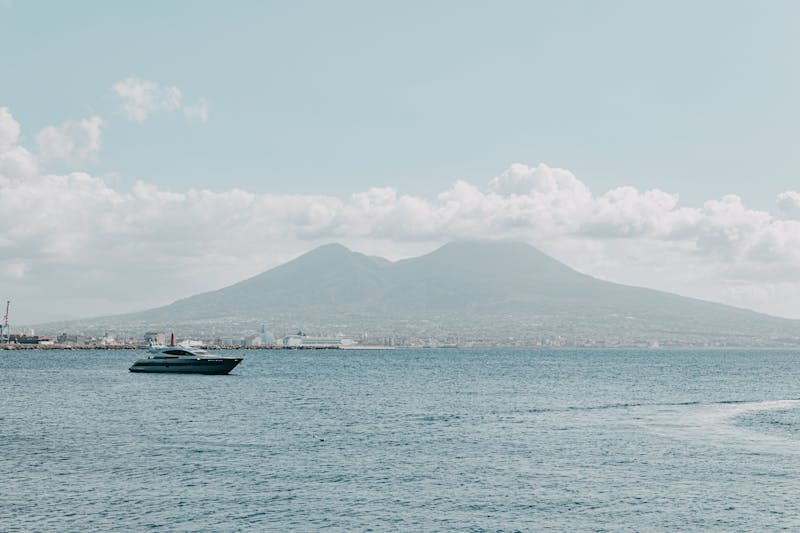 Yacht sailing on the ocean near Naples with Mount Vesuvius visible in the background