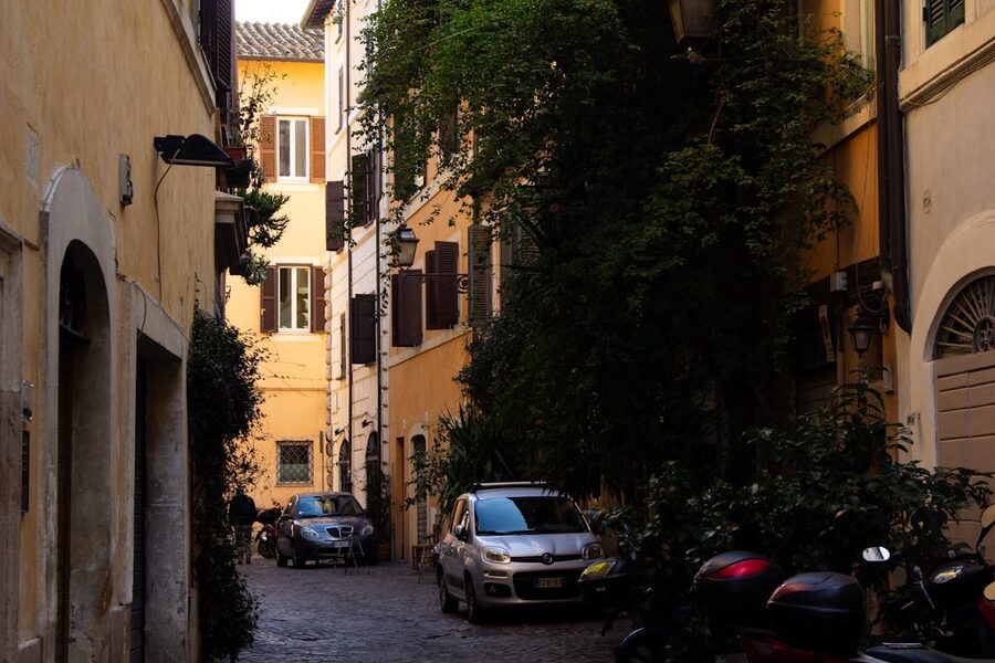 A narrow cobblestone alley lined with historic buildings and greenery in Rome