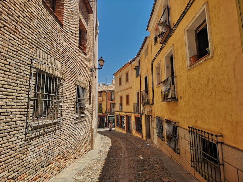 Picturesque narrow alley with colorful building facades in Toledo old town Spain