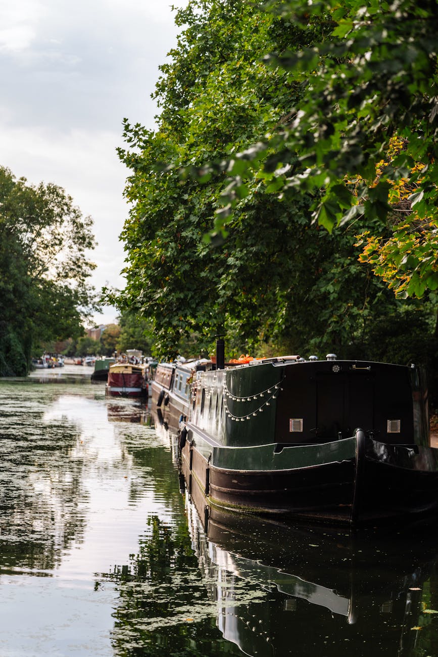 Row of narrowboats moored along a peaceful tree-lined canal in England