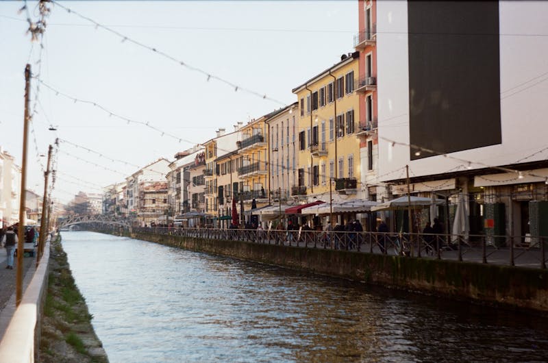 Navigli canal street with shops, string lights, and pedestrians in daylight