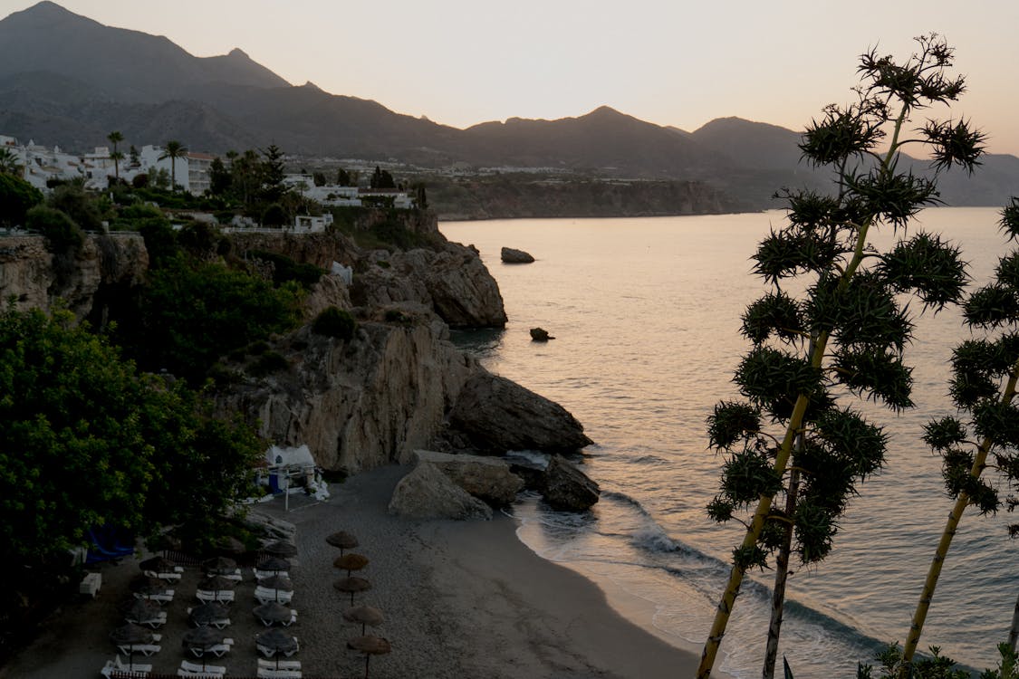 Sandy beach with cliffs and calm sunset waters near Nerja