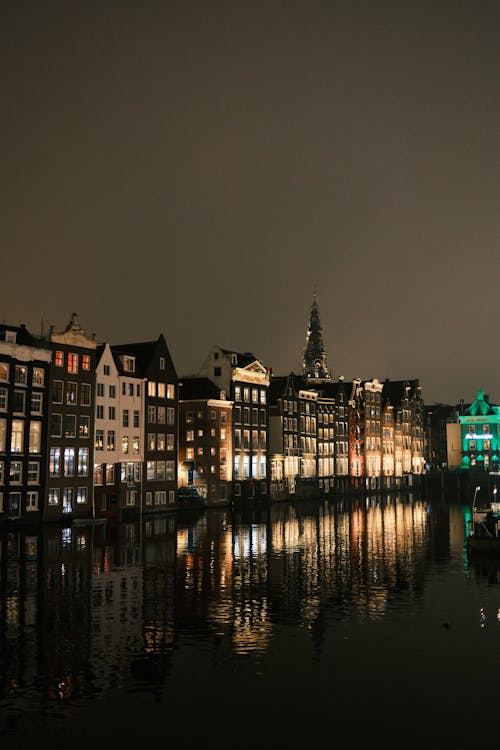 Night view of illuminated Amsterdam canal houses reflecting on still water