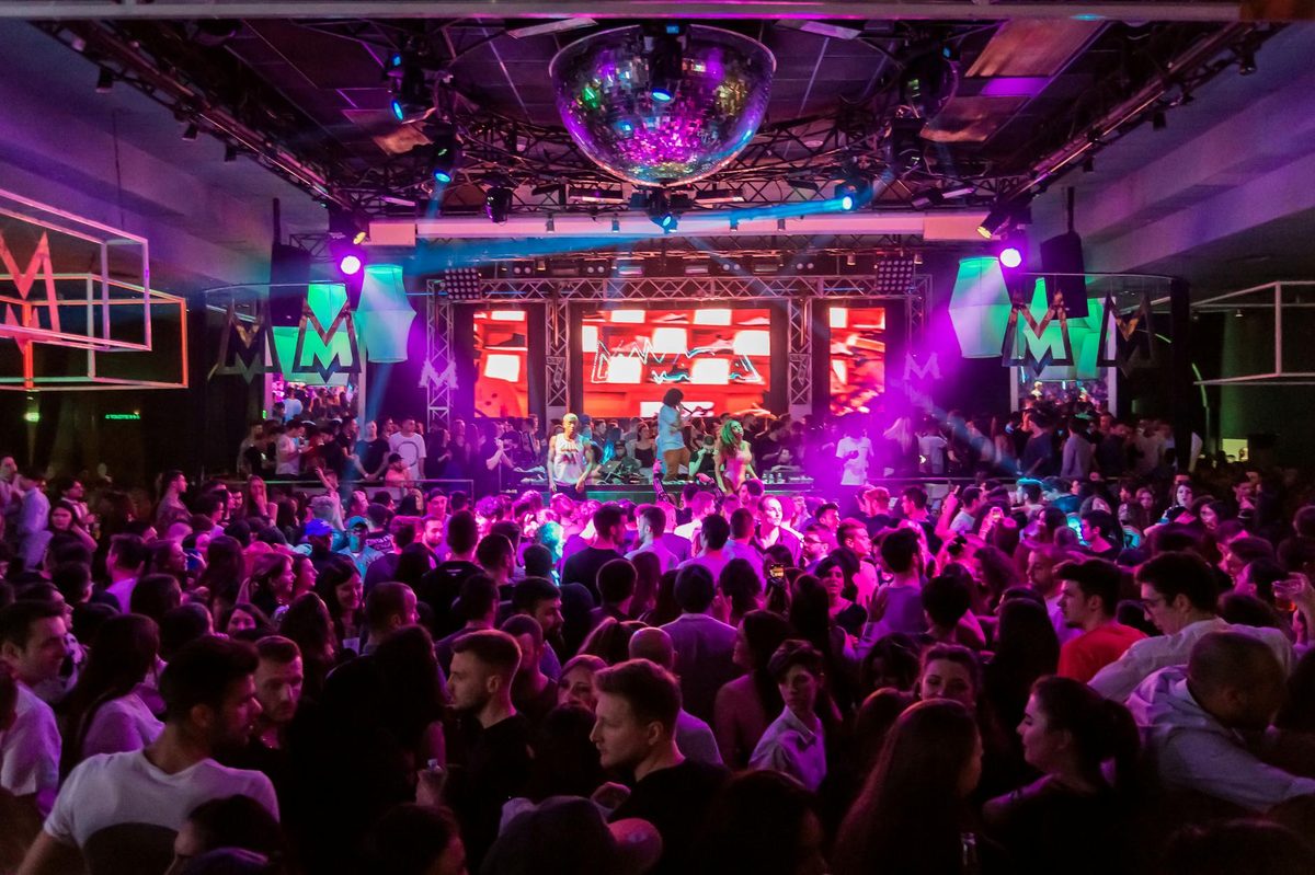 Crowd dancing at a nightclub with colorful lights