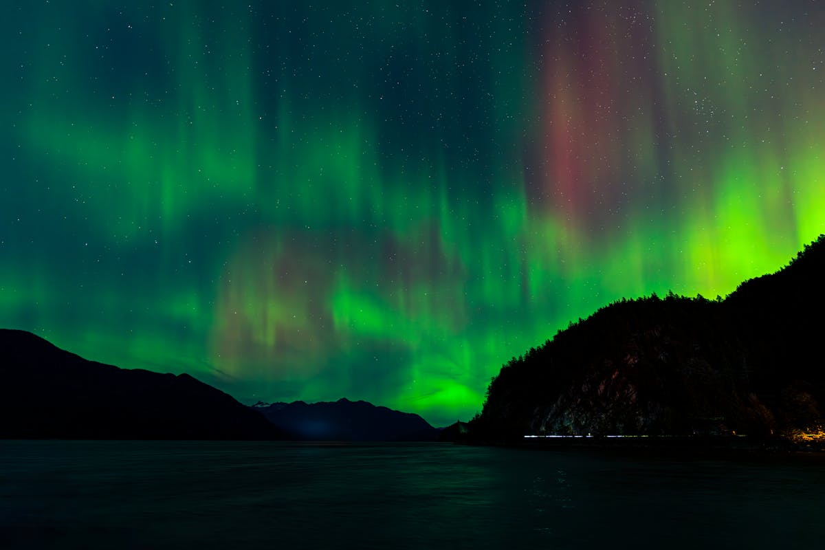 Northern Lights dancing over mountains and water in Norway