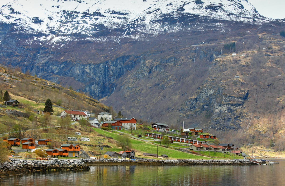 Village in Norwegian fjord surrounded by snowy mountains and tranquil waters