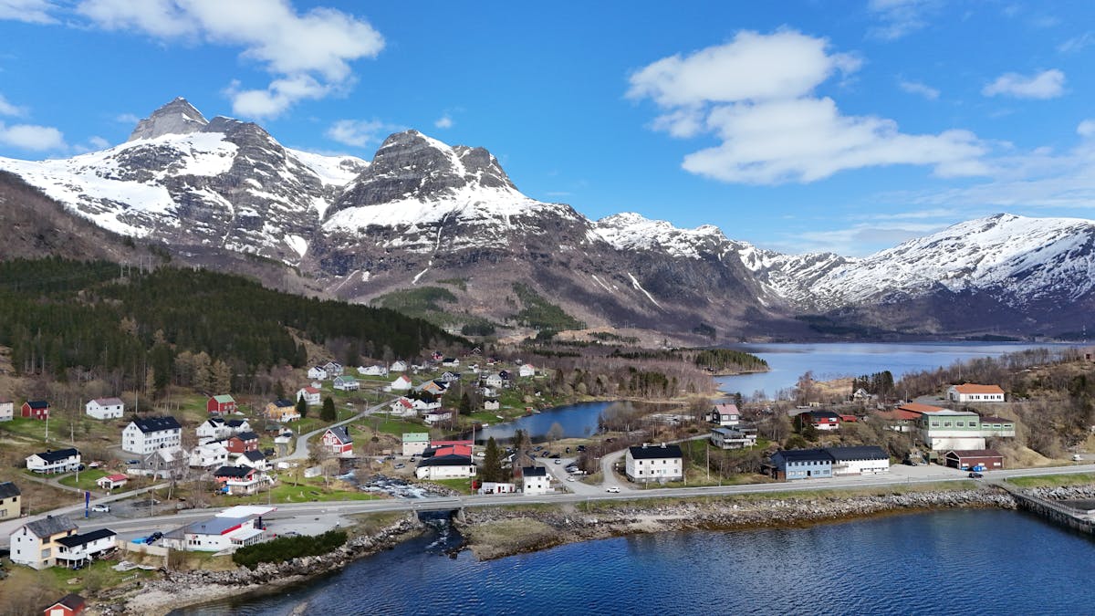 Aerial view of Norwegian village with snow-capped mountains and blue sky