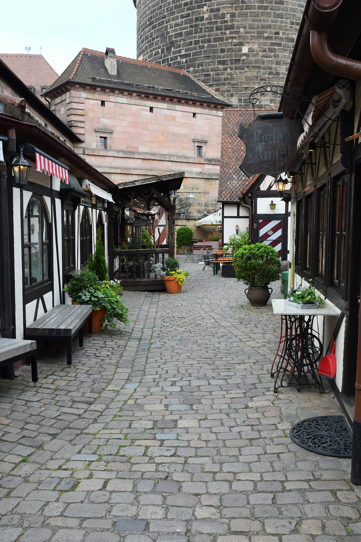 A cobblestone alleyway with potted plants in Nuremberg Old Town