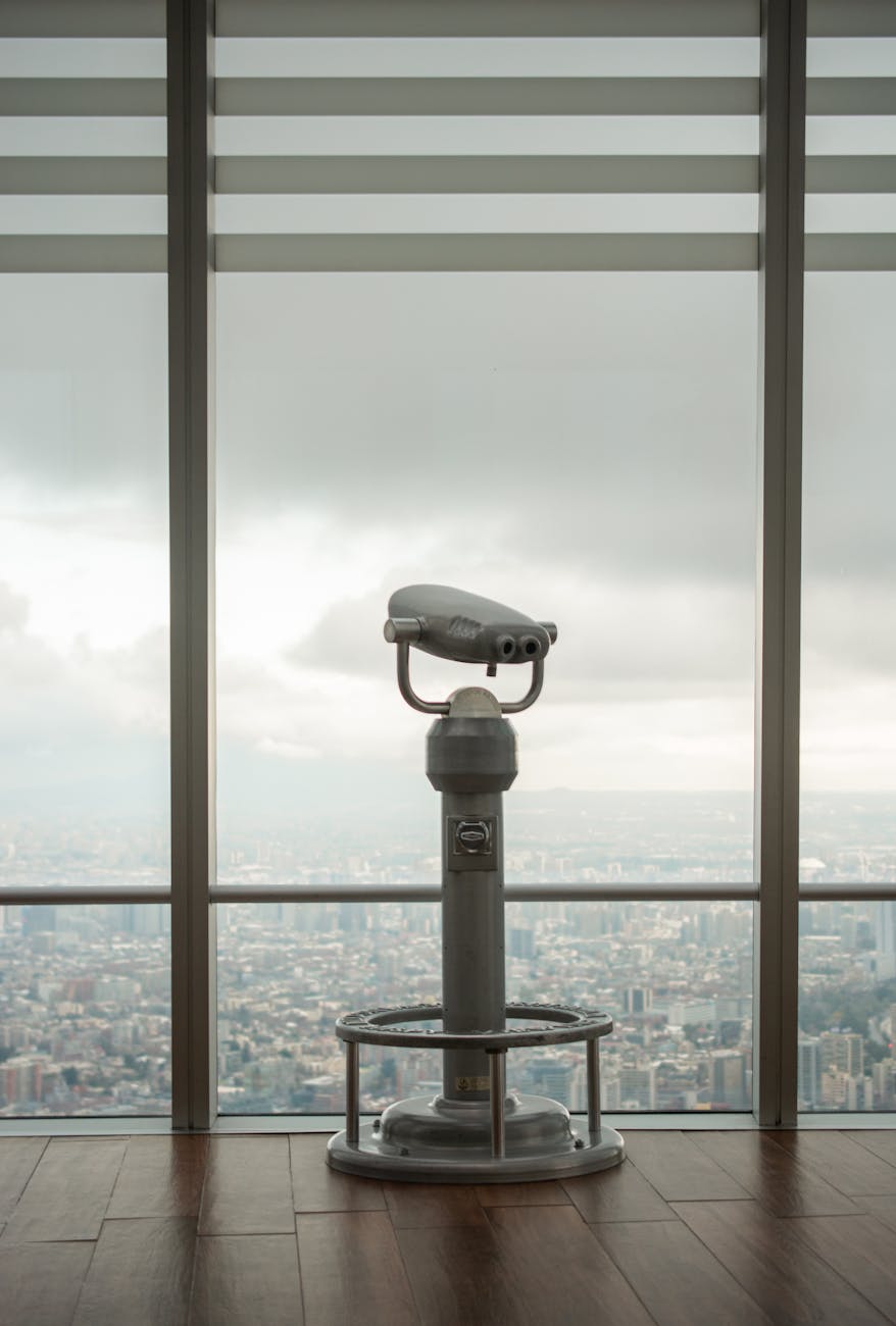 Stationary binoculars on an observation deck overlooking a modern city