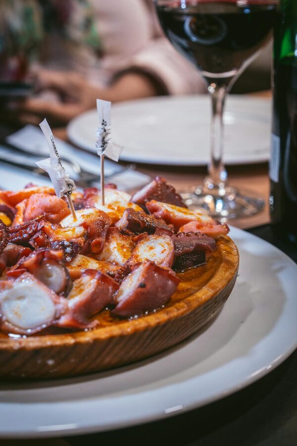 Freshly prepared octopus dish served with red wine at a Galician restaurant