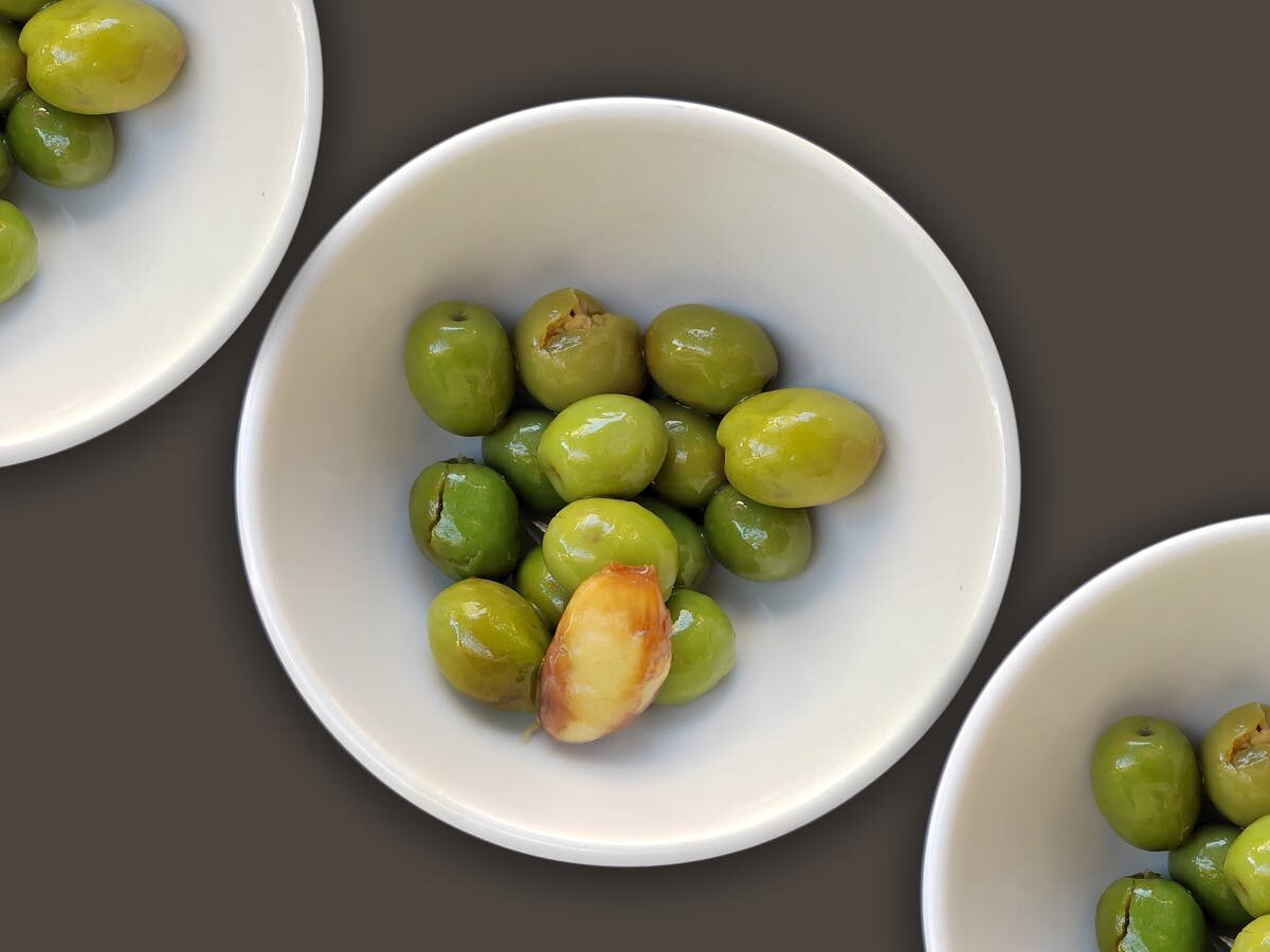 Bowls of marinated green olives with garlic clove as a traditional Spanish appetizer
