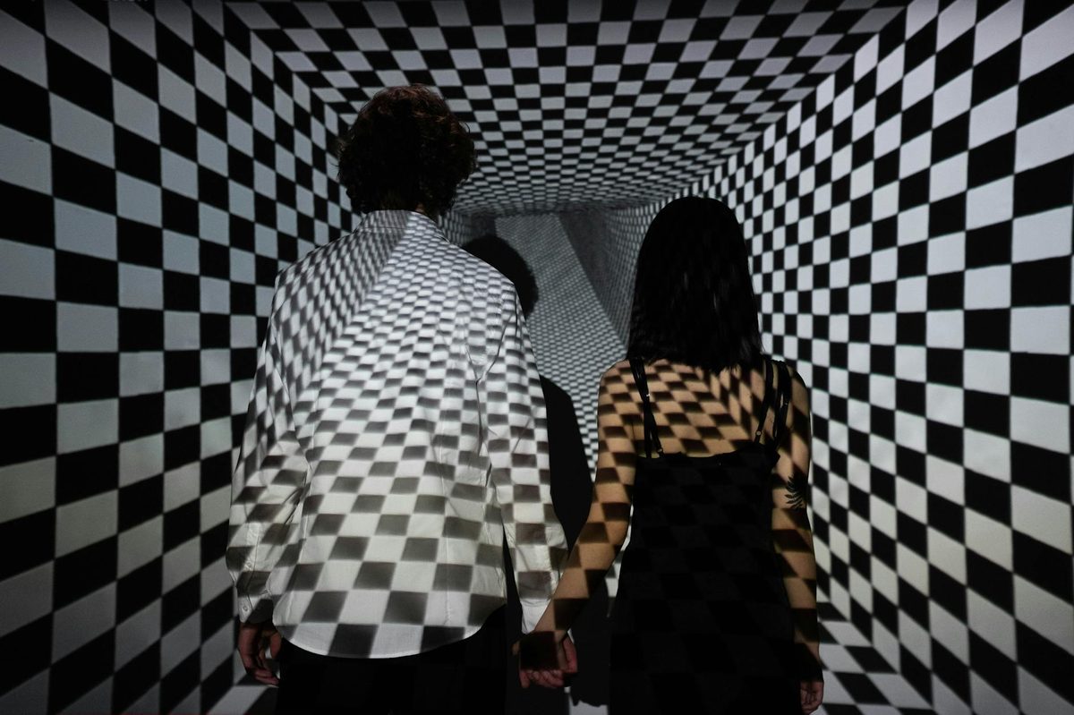 Two people in a black and white checkerboard tunnel illusion