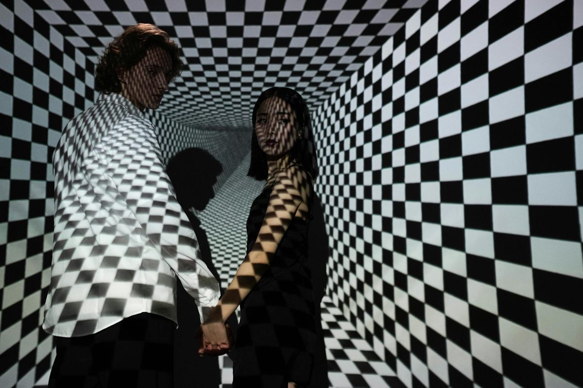 A couple in a checkered tunnel optical illusion