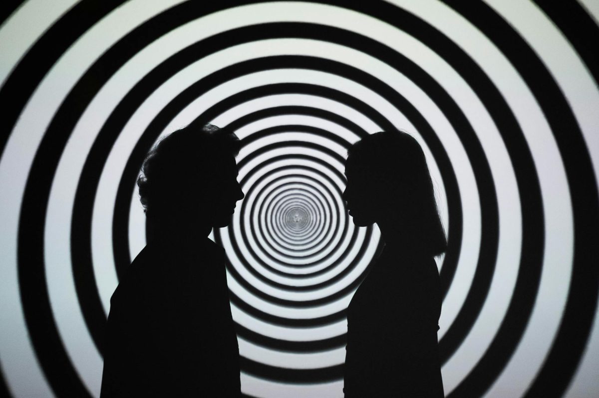 Silhouettes against a hypnotic spiral optical illusion