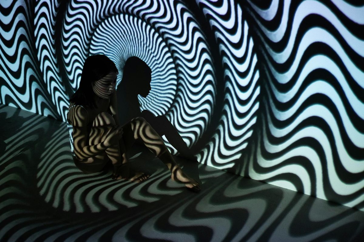 A person in a surreal room with black and white wavy patterns