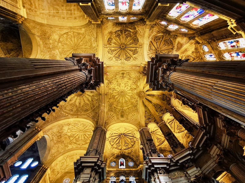 Interior view of Malaga Cathedral showing the ornate painted ceiling columns and nave