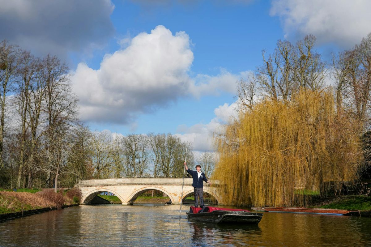 Person punting under a stone bridge in Oxford