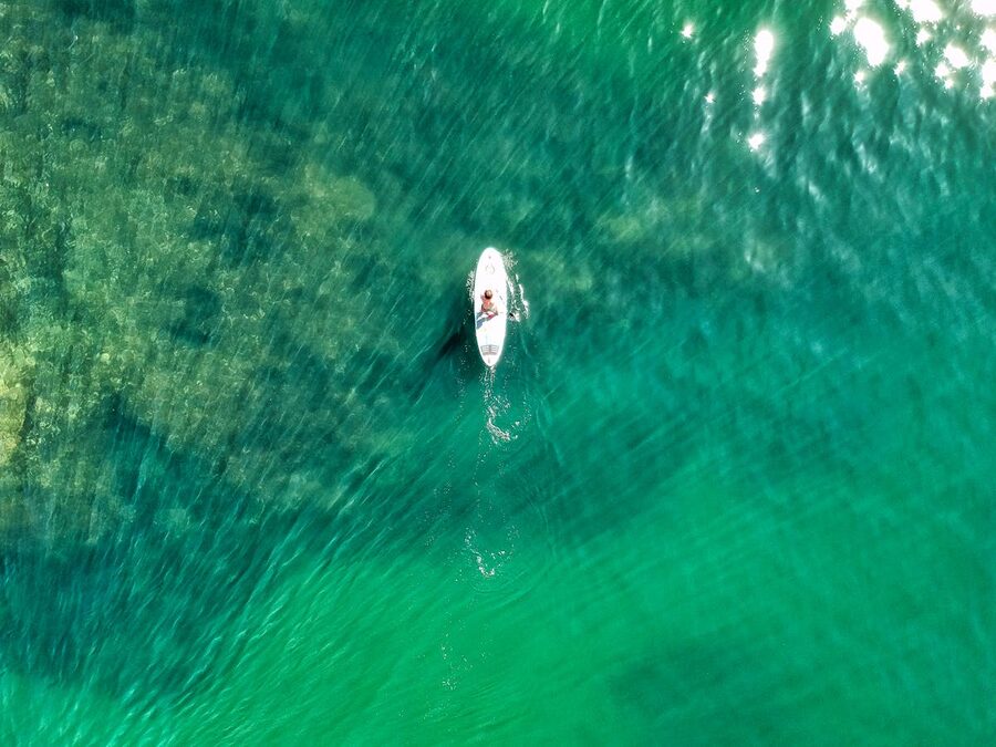 Drone shot of a lone paddleboarder on turquoise ocean water