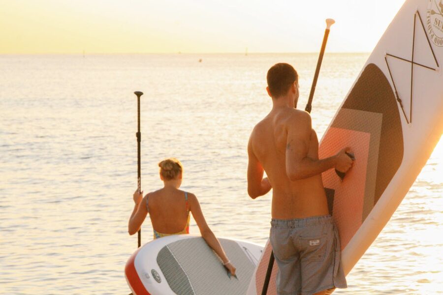 Couple enjoying paddleboarding at sunset on a serene Mediterranean beach