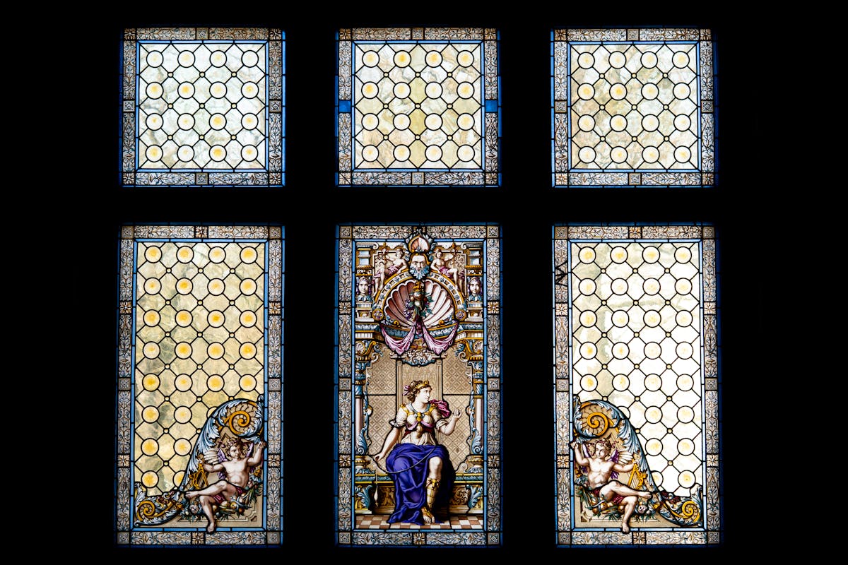Intricate stained glass windows with artistic designs inside a palace interior