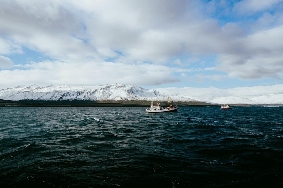 Panoramic view of Eyjafjörður fjord in Iceland with snow-capped mountains and boats on the water.