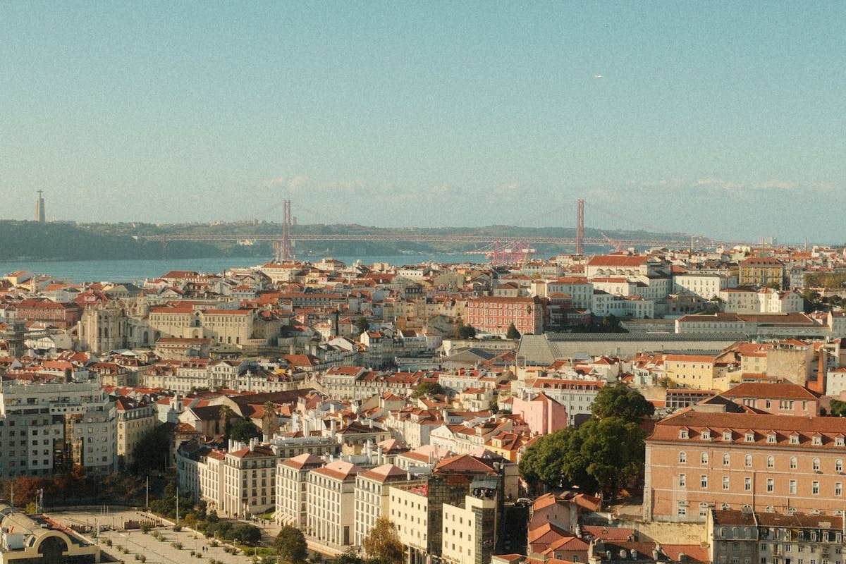 Wide panoramic view of Lisbon showing the 25 de Abril Bridge and Cristo Rei statue across the river