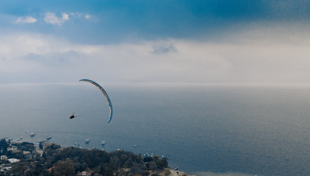 Aerial view of a paraglider over coastal landscape with ocean