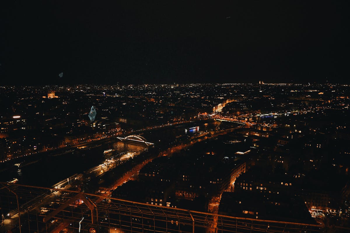 Panoramic night view of Paris cityscape from the Eiffel Tower showing illuminated bridges and streets