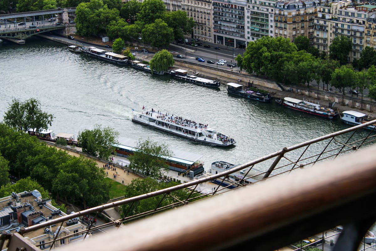 Aerial view of a cruise boat on the Seine River in Paris with tree-lined banks