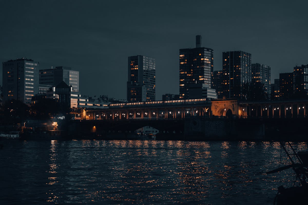 Nighttime view of Paris skyline with illuminated buildings reflecting on the Seine