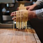 Chef hands holding freshly made pasta in a kitchen