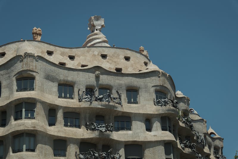 Ornate balconies and stone facade of Casa Mila La Pedrera against blue sky in Barcelona