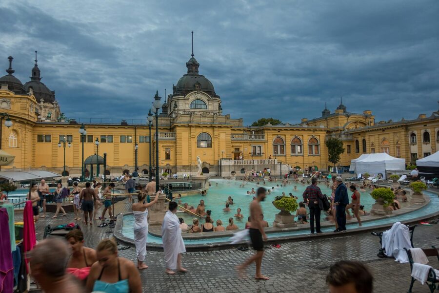 People enjoying Széchenyi Thermal Bath in Budapest with iconic yellow facade