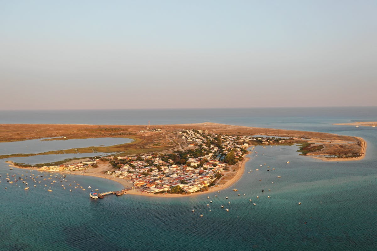 Aerial view of the Algarve coastline near Olhão with sandbar islands and calm lagoon waters at golden hour