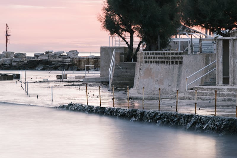 Tranquil coastal view in Puglia Italy at dusk with soft pink and purple skies over the sea